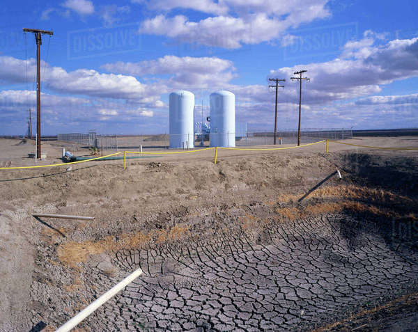 Dry drainage ditch near silos - Stock Photo - Dissolve