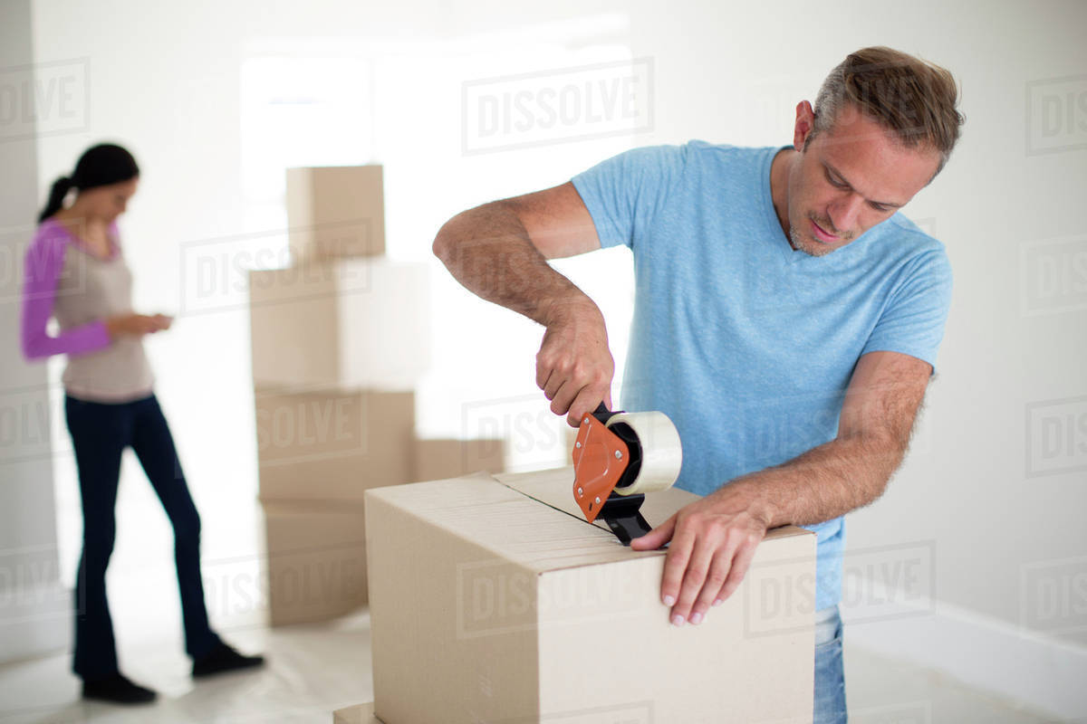 Man taping cardboard box to move - Stock Photo - Dissolve
