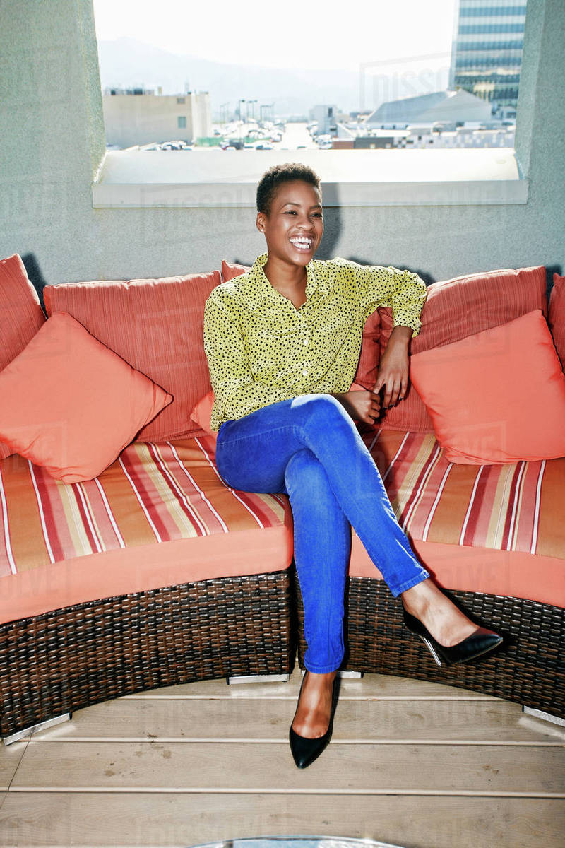 Black woman sitting on rooftop sofa - Royalty-free Stock Photo | Dissolve