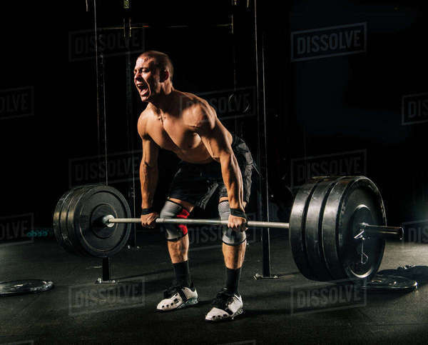 Man screaming while lifting heavy barbell in gymnasium - Royalty-free ...