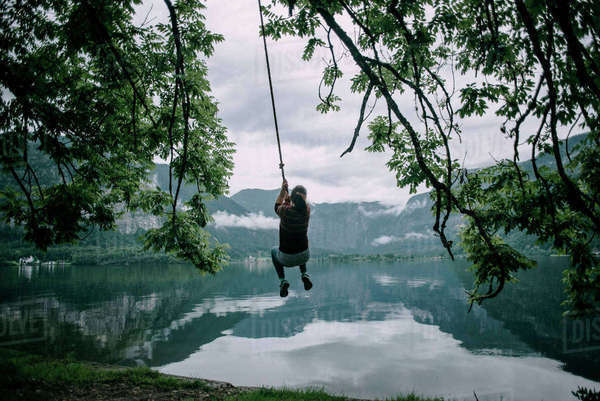 Caucasian woman swinging on rope swing at lake - Royalty-free Stock ...