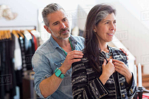 Man helping woman with jacket in store - Stock Photo - Dissolve