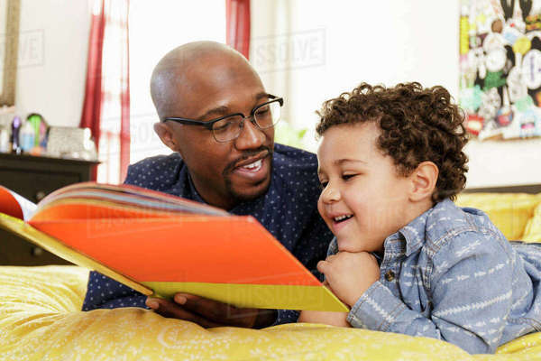 Father reading book to son on bed - Royalty-free Stock Photo | Dissolve