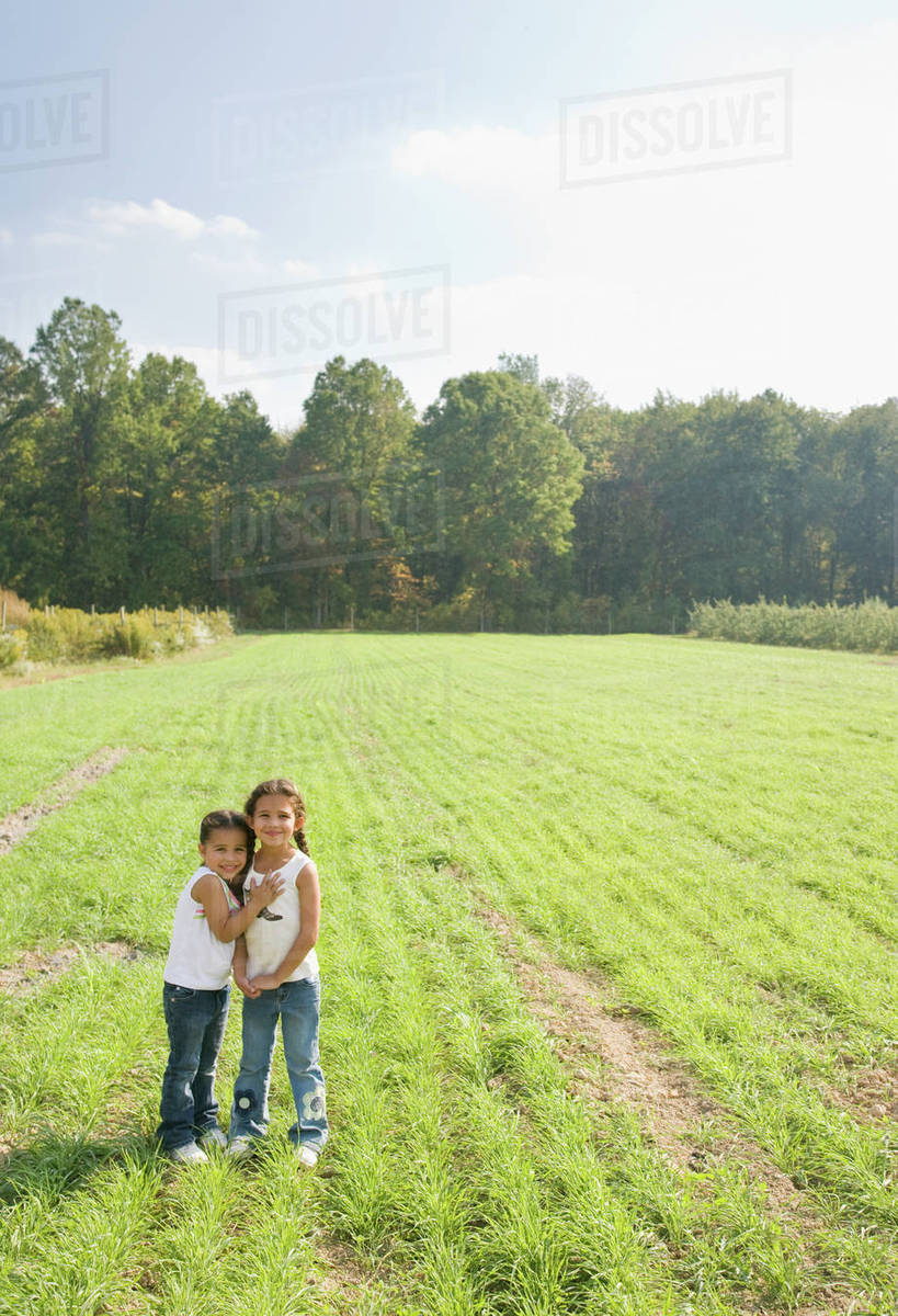 Hispanic sisters hugging in field - Royalty-free Stock Photo | Dissolve