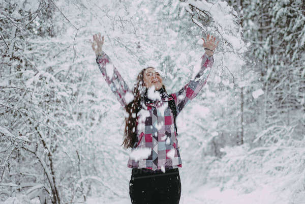 Snow falling on woman in forest - Royalty-free Stock Photo | Dissolve