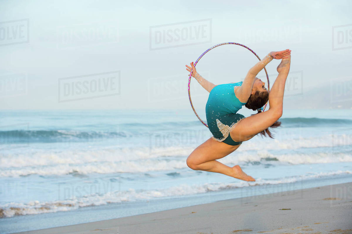 Gymnast jumping with hoop on beach - Stock Photo - Dissolve