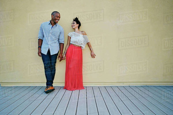 Couple standing against wall outdoors - Royalty-free Stock Photo | Dissolve