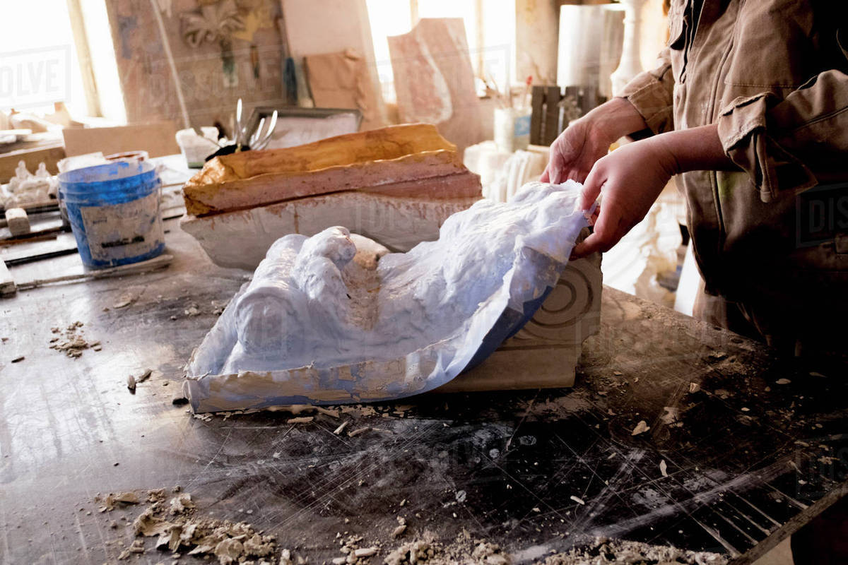 Caucasian artist lifting mold from plaster - Stock Photo - Dissolve