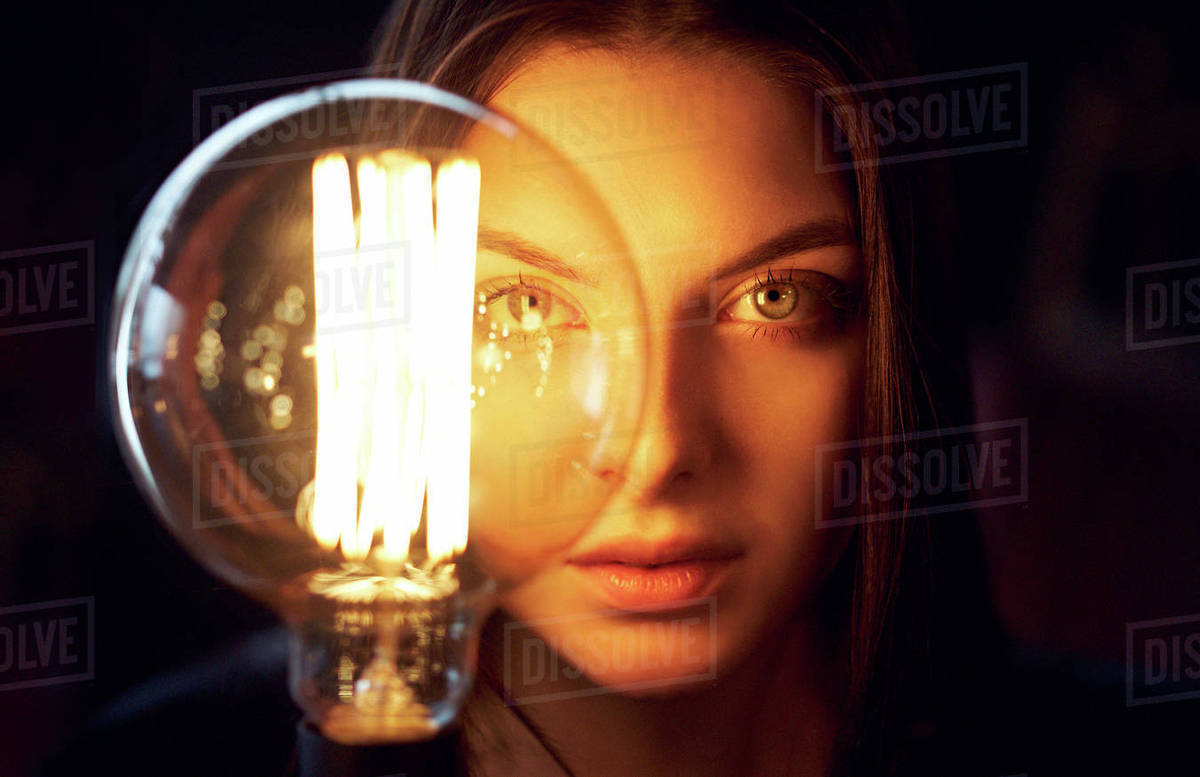 Face of Caucasian woman illuminated by energy efficient light bulb ...