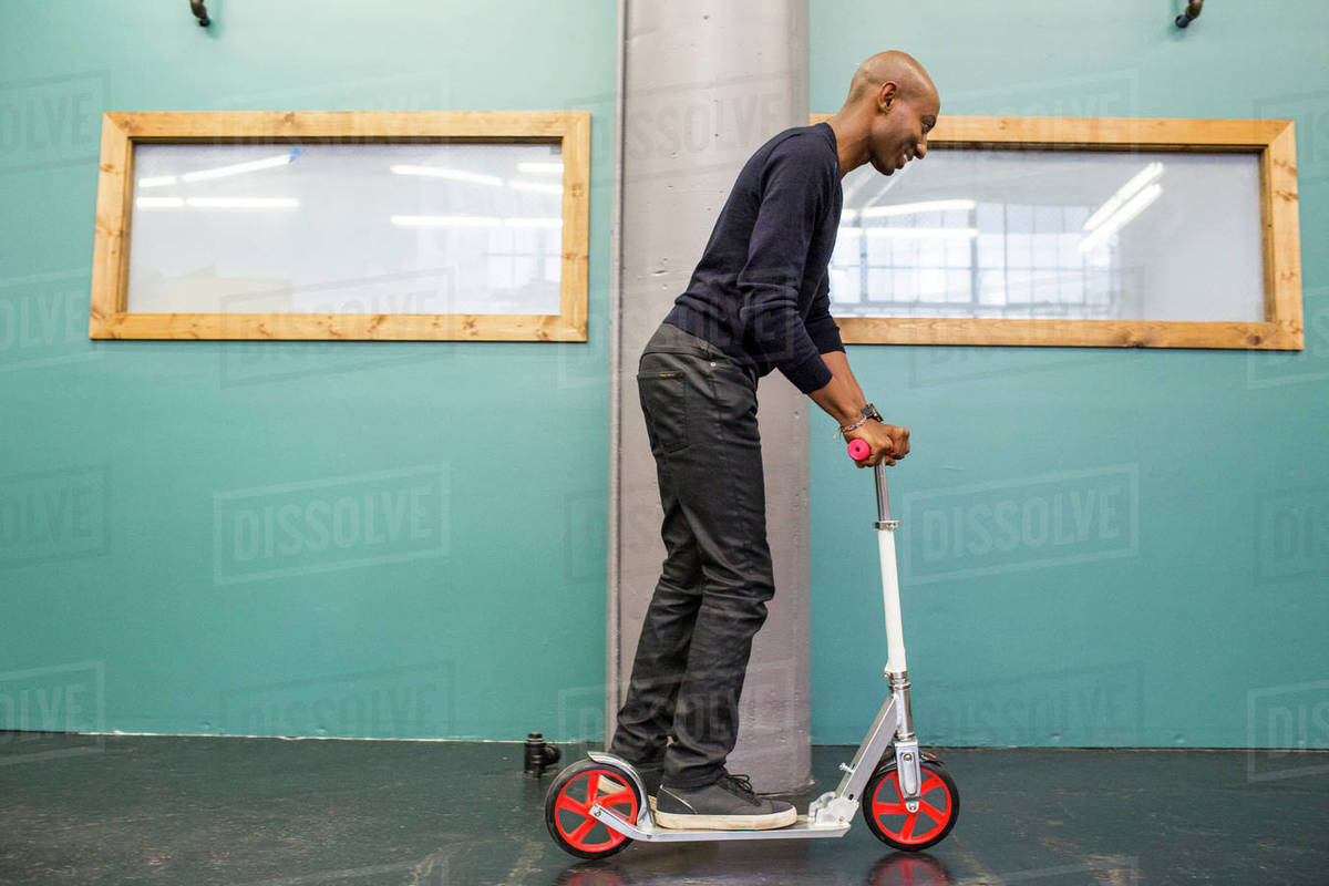 African American man riding scooter indoors - Royalty-free Stock Photo ...