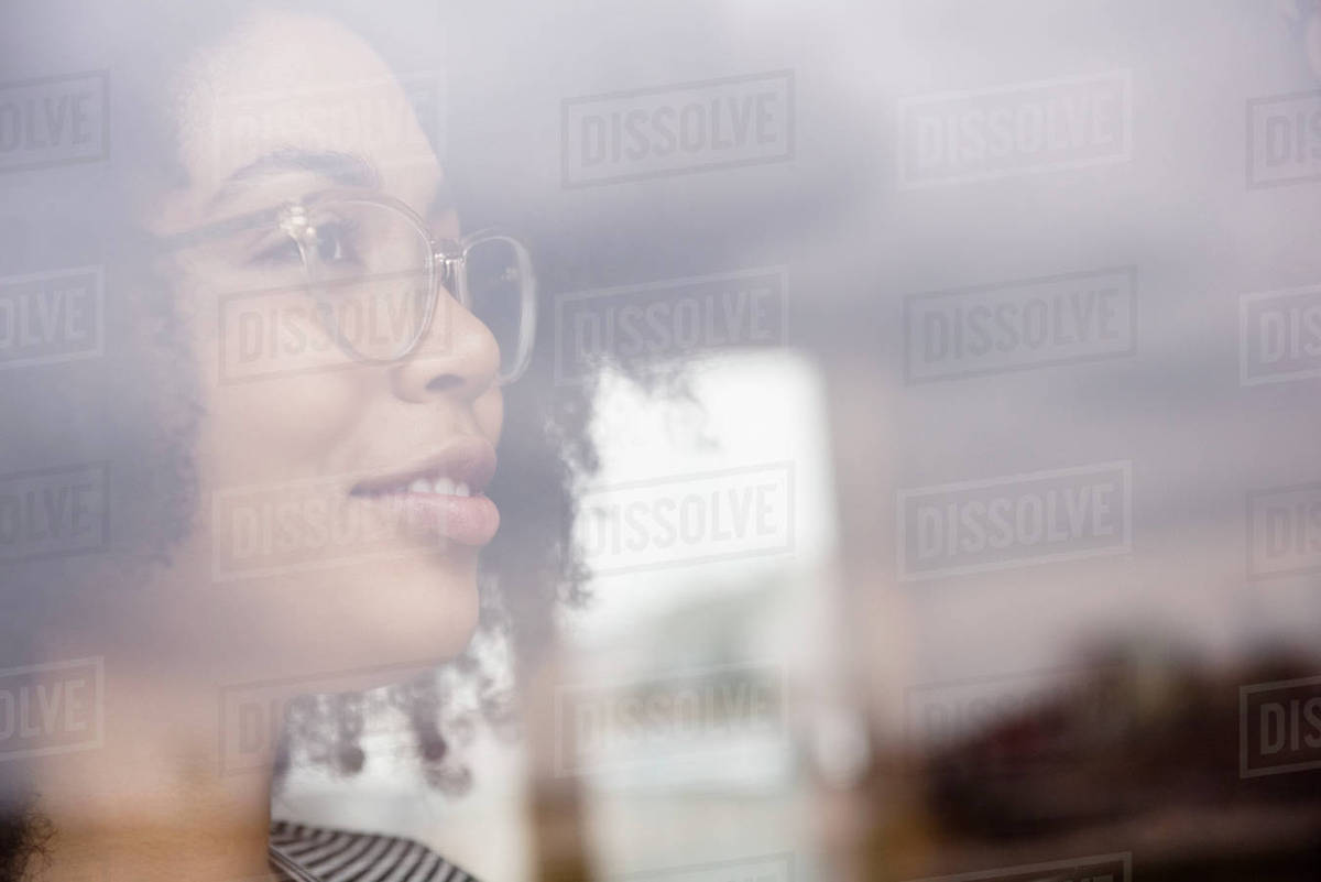 Smiling African American woman behind window - Stock Photo - Dissolve