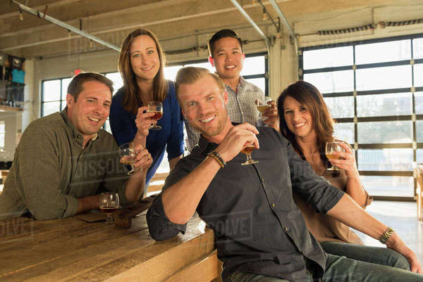 Portrait of smiling friends drinking beer in brew pub - Stock Photo ...
