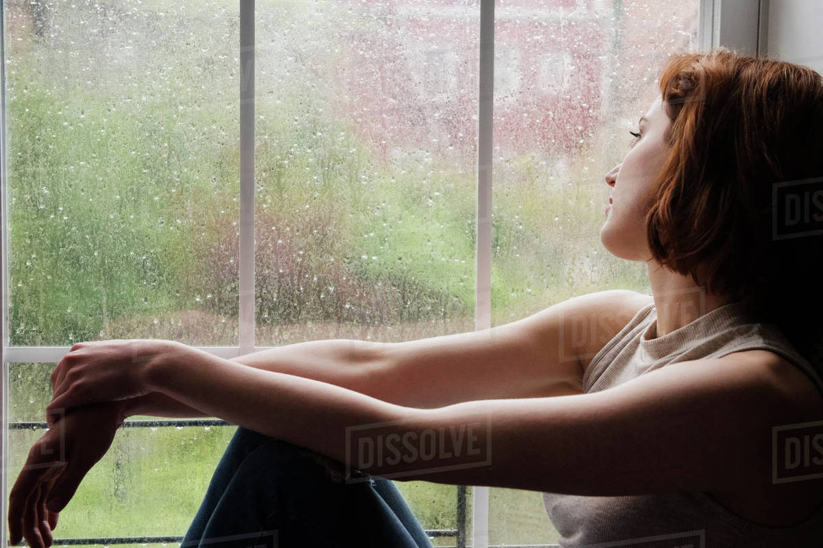 Caucasian woman sitting near rainy window daydreaming - Stock Photo ...