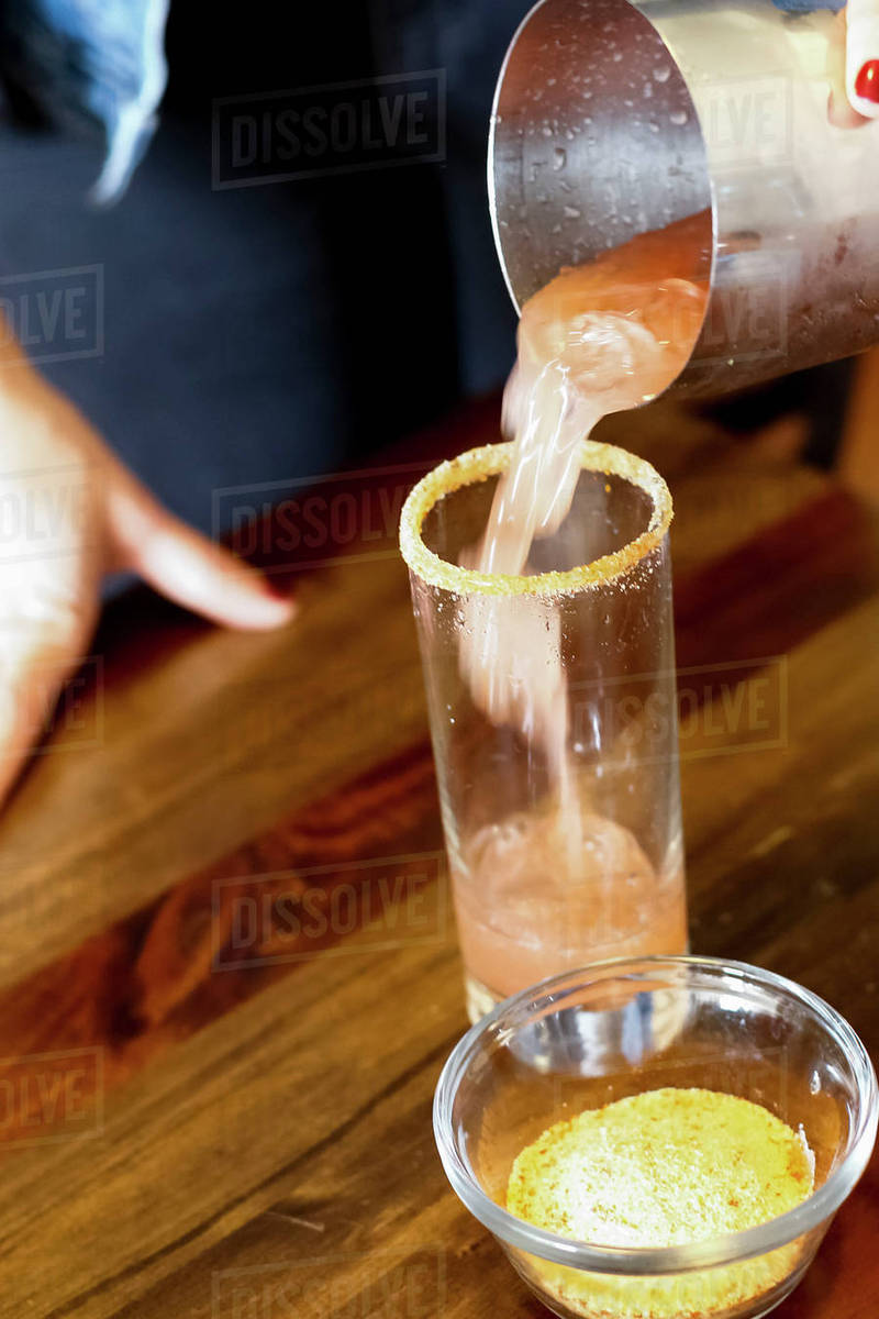 Woman pouring cocktail into the glass - Stock Photo - Dissolve