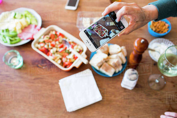 Woman photographing appetizers on table with cell phone - Royalty-free ...