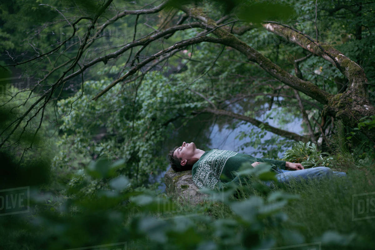 Caucasian man relaxing in woods - Stock Photo - Dissolve