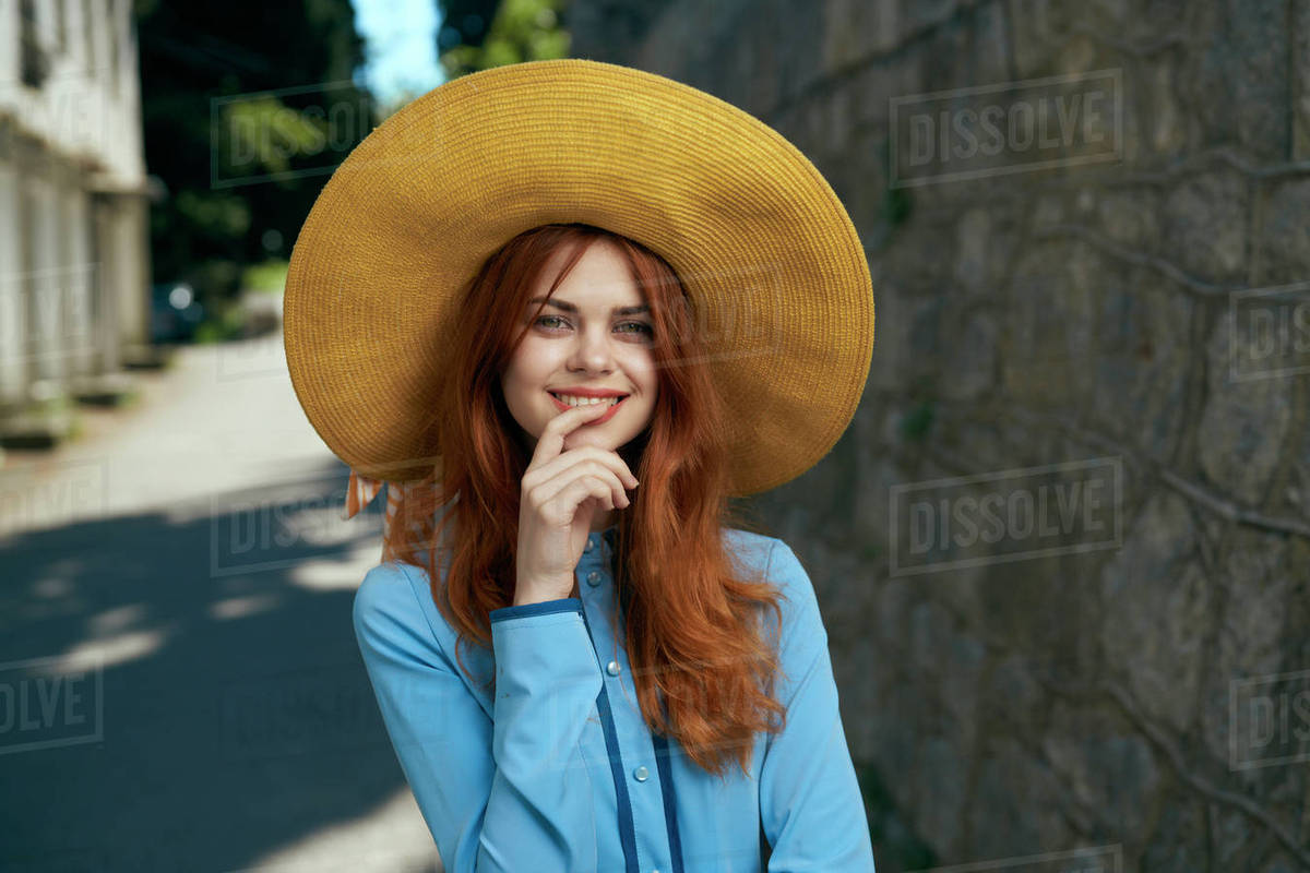 Smiling Caucasian woman wearing hat near stone wall - Royalty-free ...