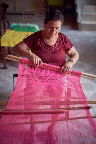 Hispanic woman weaving fabric on loom - Stock Photo - Dissolve