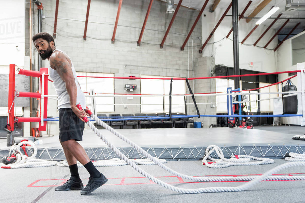 Black man pulling heavy ropes in gymnasium - Stock Photo - Dissolve