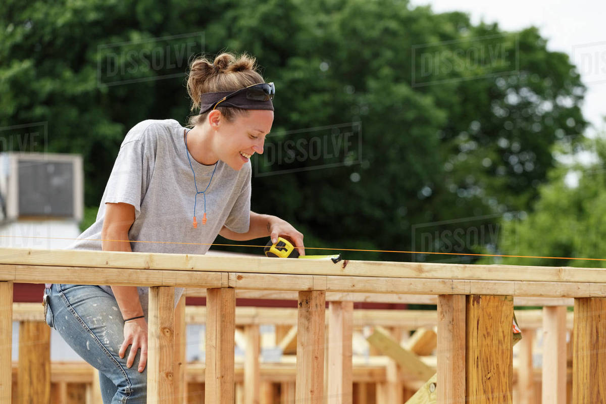 Caucasian woman measuring at construction site - Stock Photo - Dissolve