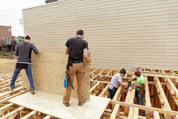 Volunteers holding plywood at construction site - Royalty-free Stock ...