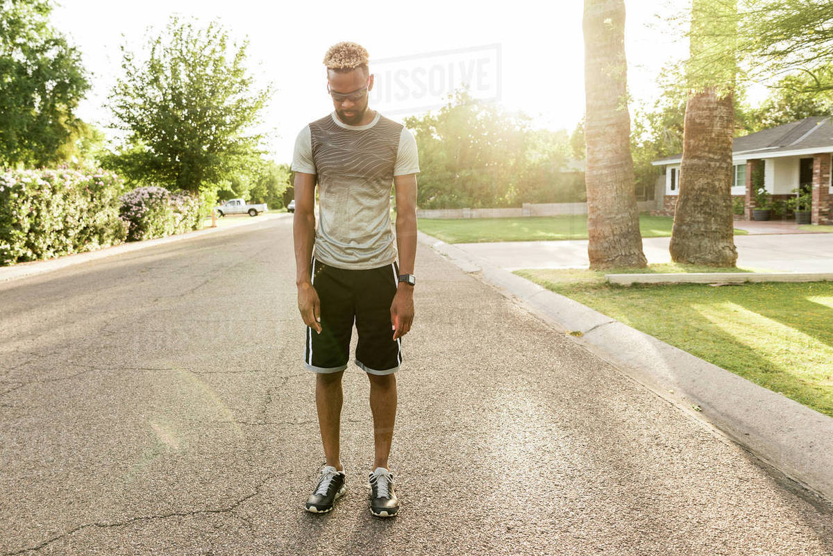 Black man standing on street in the neighborhood looking down - Stock ...