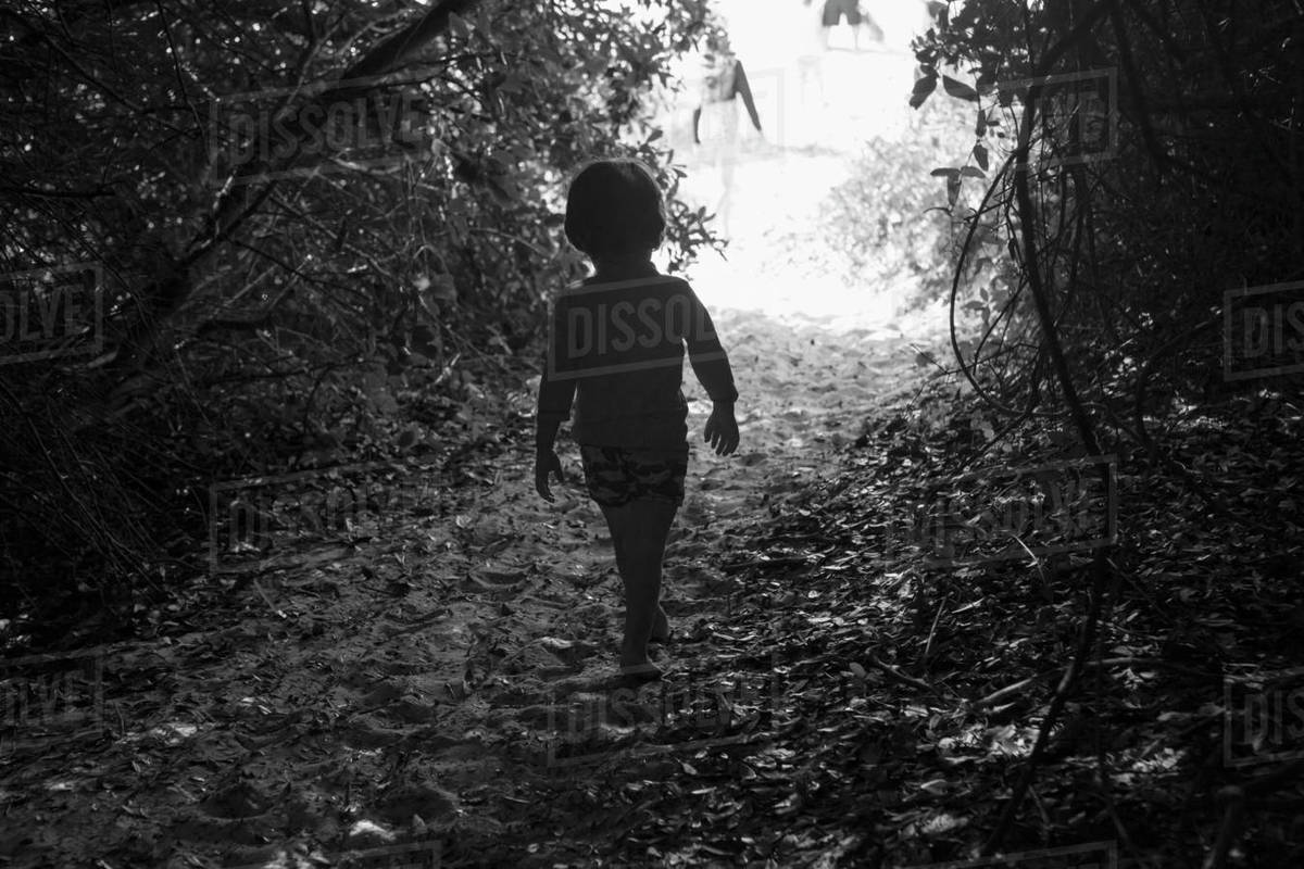 Caucasian boy walking on sandy path - Royalty-free Stock Photo | Dissolve