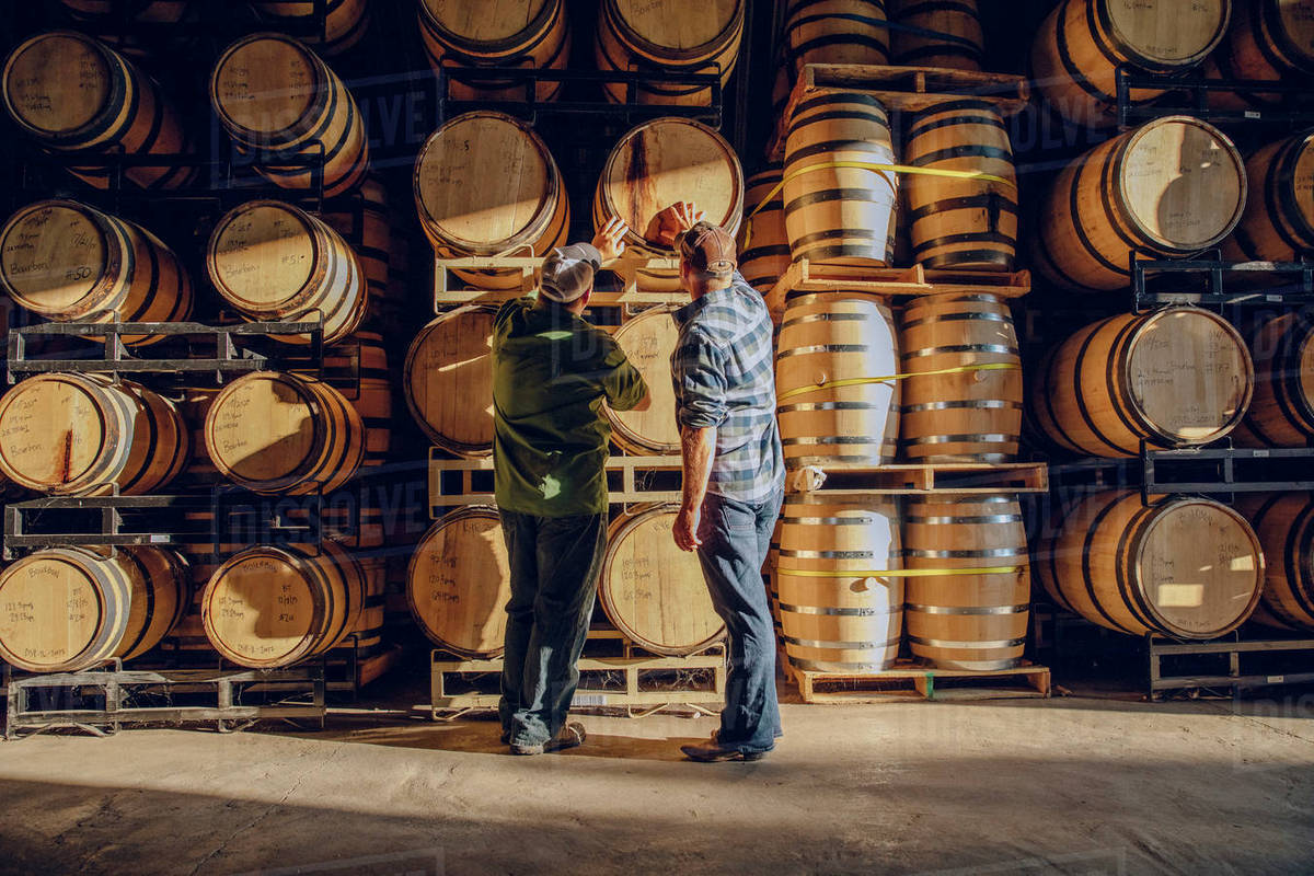 Caucasian men examining barrel in distillery - Royalty-free Stock Photo ...