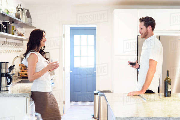 Smiling Caucasian couple drinking red wine in kitchen - Stock Photo ...