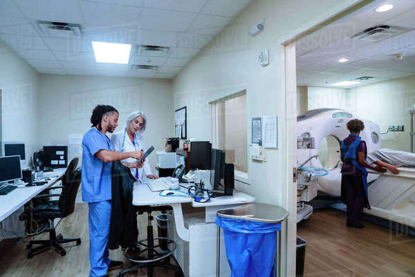 Doctor and nurse discussing digital tablet near scanner - Royalty-free ...