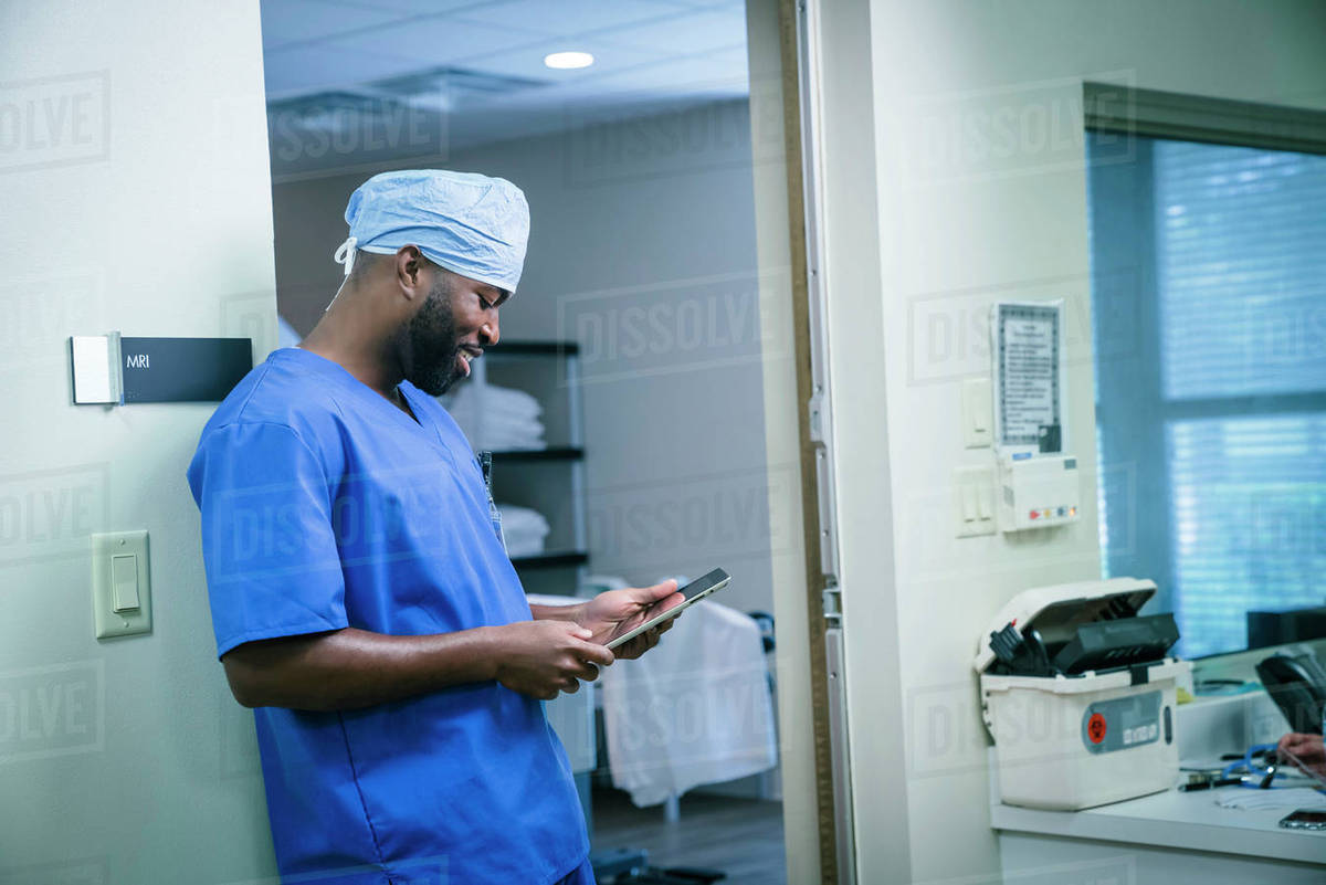 Smiling black nurse using digital tablet - Stock Photo - Dissolve
