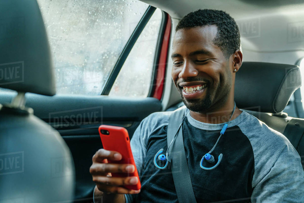 Smiling Black man texting on cell phone in car - Stock Photo - Dissolve