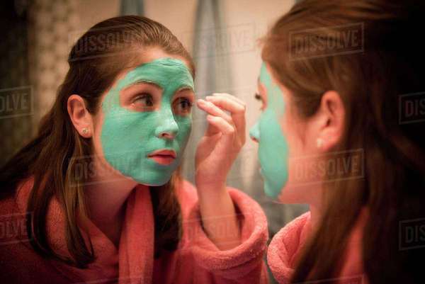 Caucasian girl applying facial mask in mirror - Royalty-free Stock ...
