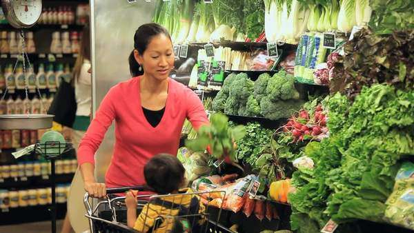 People buying produce in grocery store and worker helping customers ...