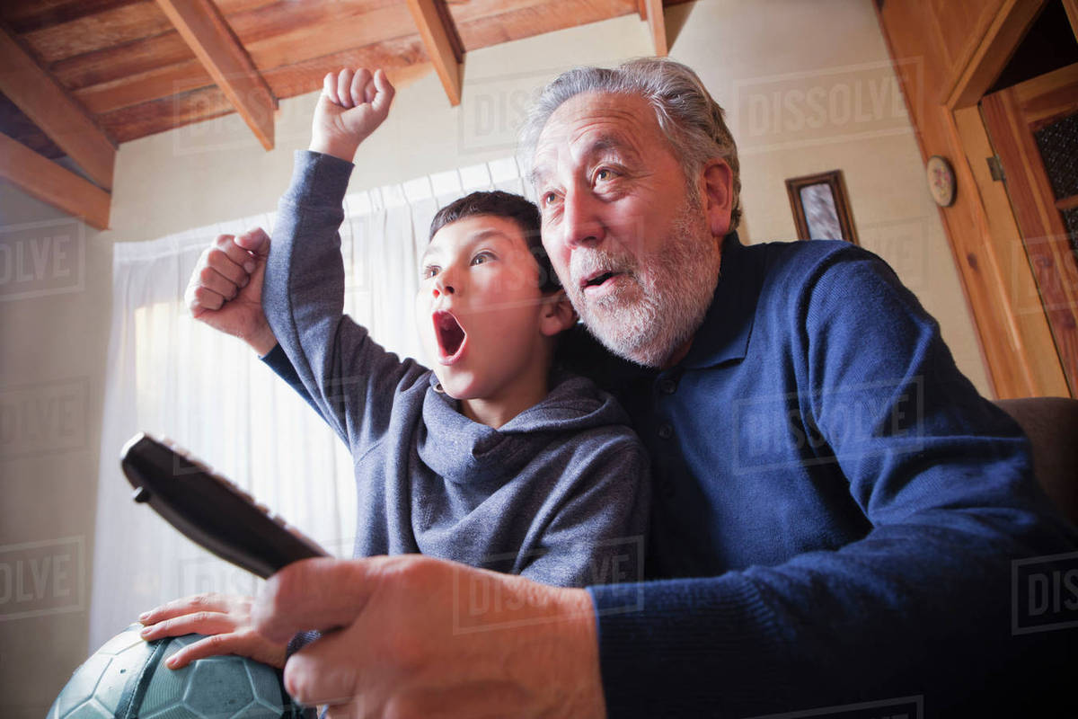 Hispanic grandfather and grandson cheering for soccer game on ...