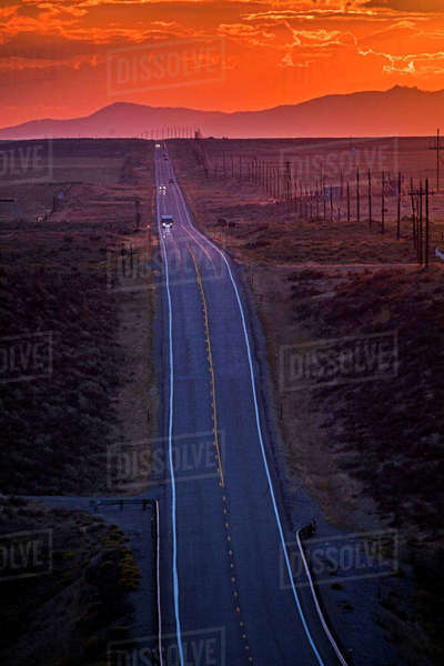 Cars driving on remote road at sunset - Stock Photo - Dissolve