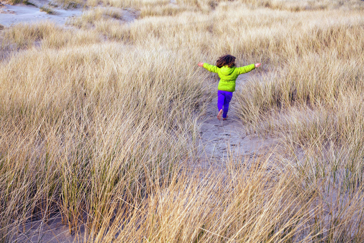 Caucasian girl running in grassy sand dune - Stock Photo - Dissolve