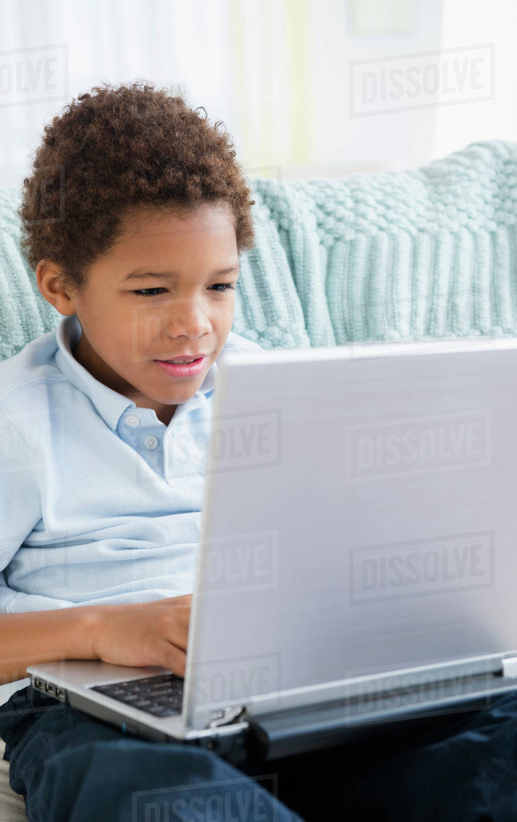 Black boy using laptop in living room - Royalty-free Stock Photo | Dissolve