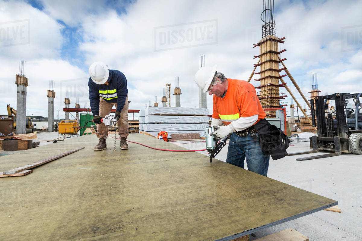 Caucasian workers drilling plant at construction site - Stock Photo ...