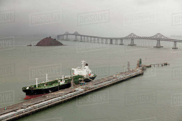 Oil tanker offloading in urban dock - Stock Photo - Dissolve