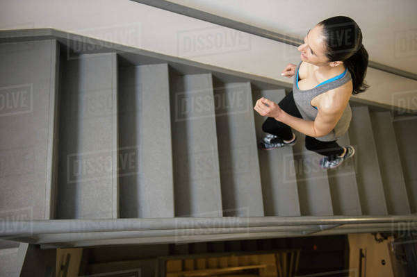 Caucasian woman running up stairs - Royalty-free Stock Photo | Dissolve