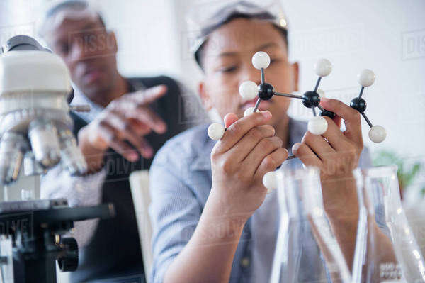 Student examining molecular model in science class - Stock Photo - Dissolve