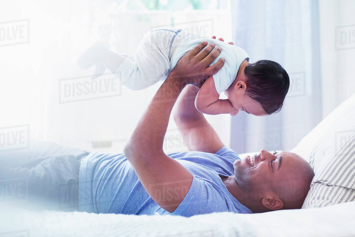 Father playing with baby on bed - Royalty-free Stock Photo | Dissolve