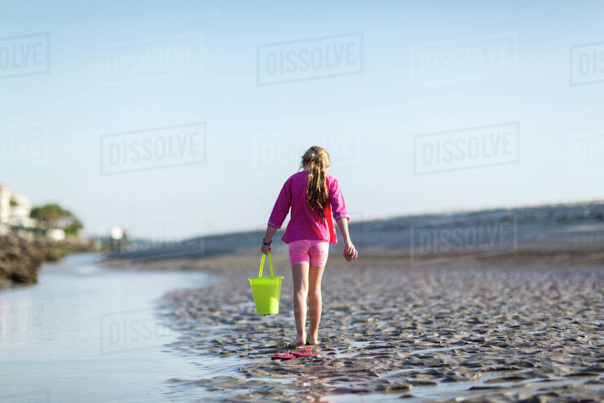 Caucasian girl carrying bucket on beach - Stock Photo - Dissolve