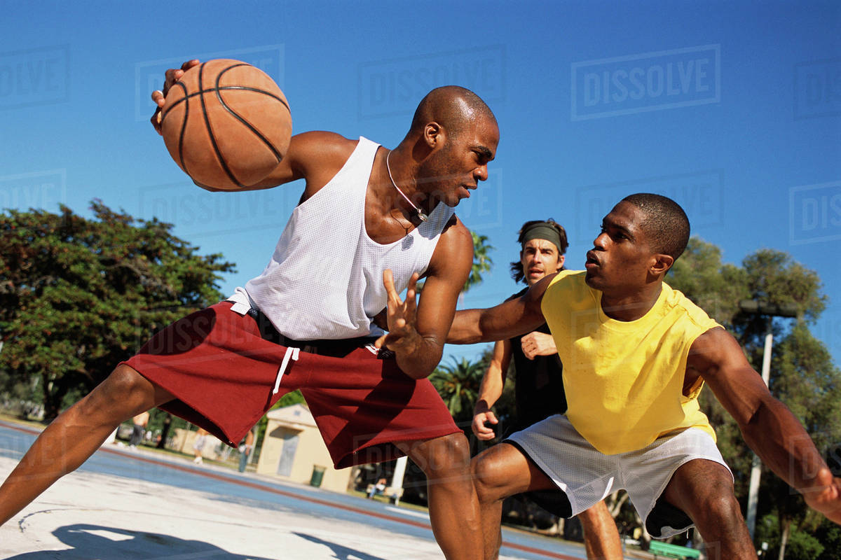 Men playing basketball outdoors - Stock Photo - Dissolve
