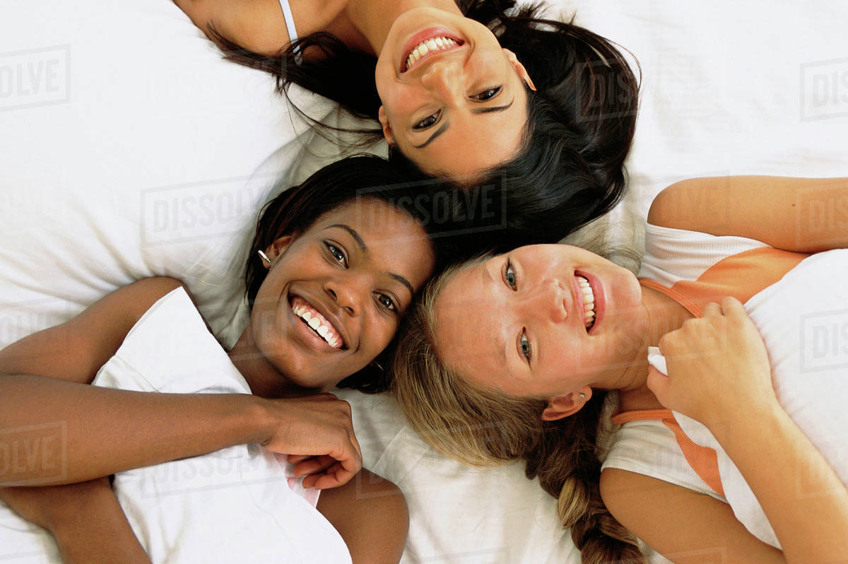 Friends relaxing together on bed - Royalty-free Stock Photo | Dissolve
