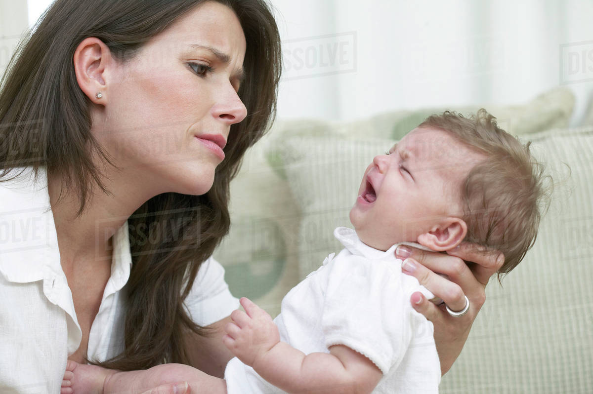 Mother comforting crying baby on sofa - Royalty-free Stock Photo | Dissolve