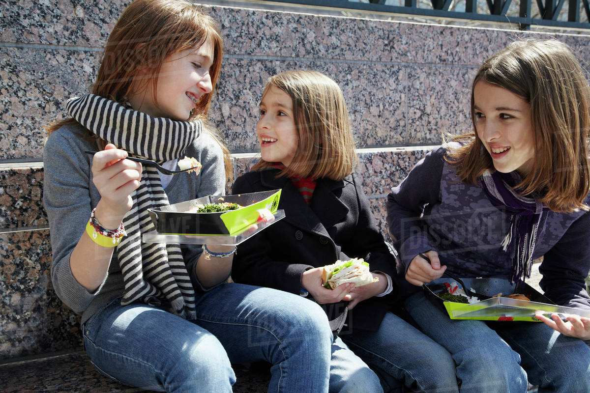 Girls eating together outdoors - Royalty-free Stock Photo | Dissolve