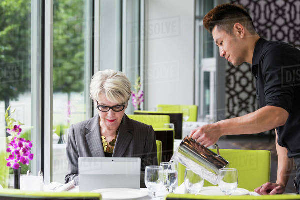 Waiter pouring water for customer in restaurant - Stock Photo - Dissolve