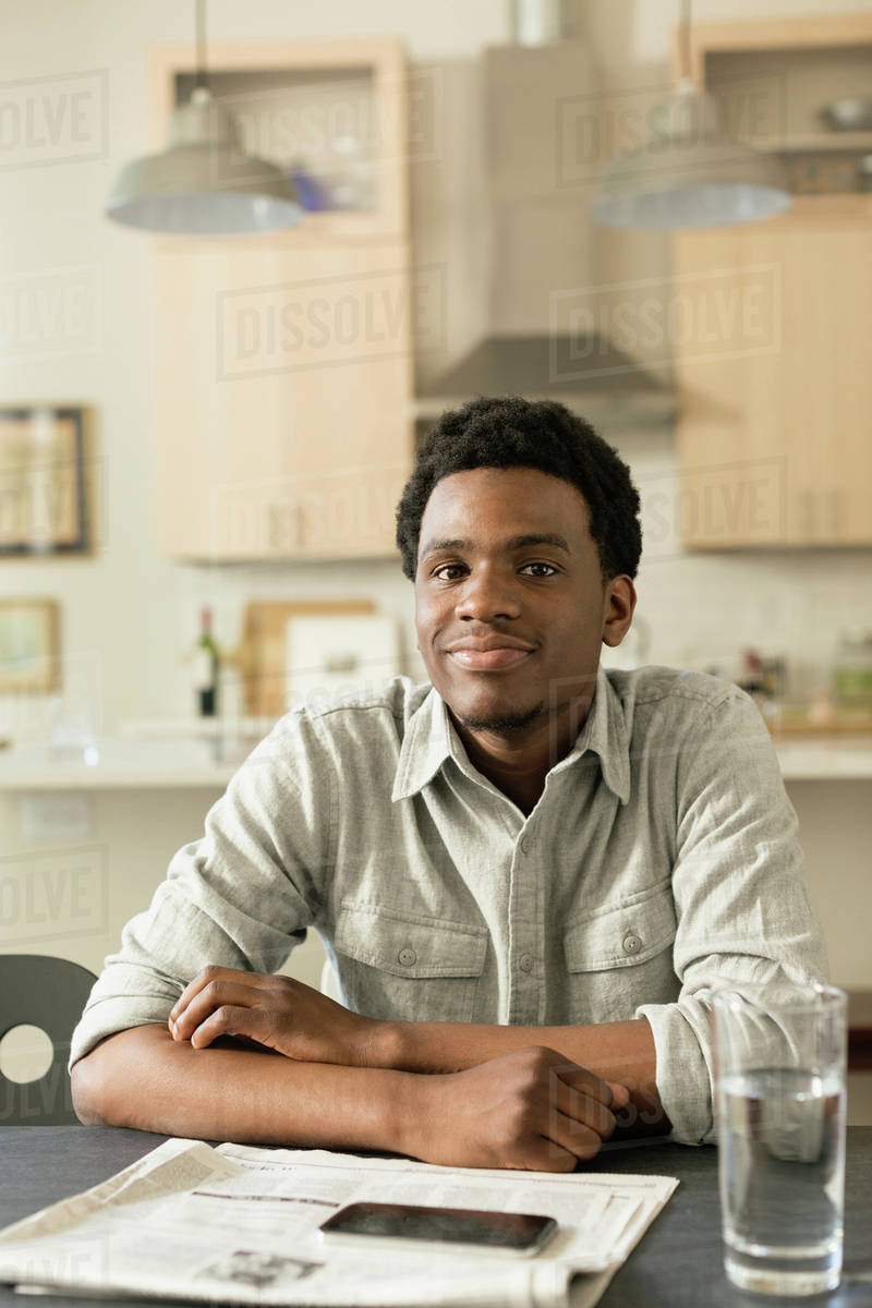 Black man reading newspaper at breakfast table - Stock Photo - Dissolve